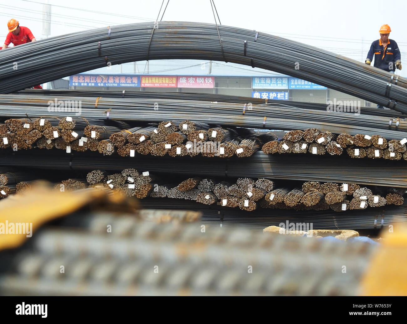--FILE--A Chinese worker directs a crane to lift reinforcing steel rods ...