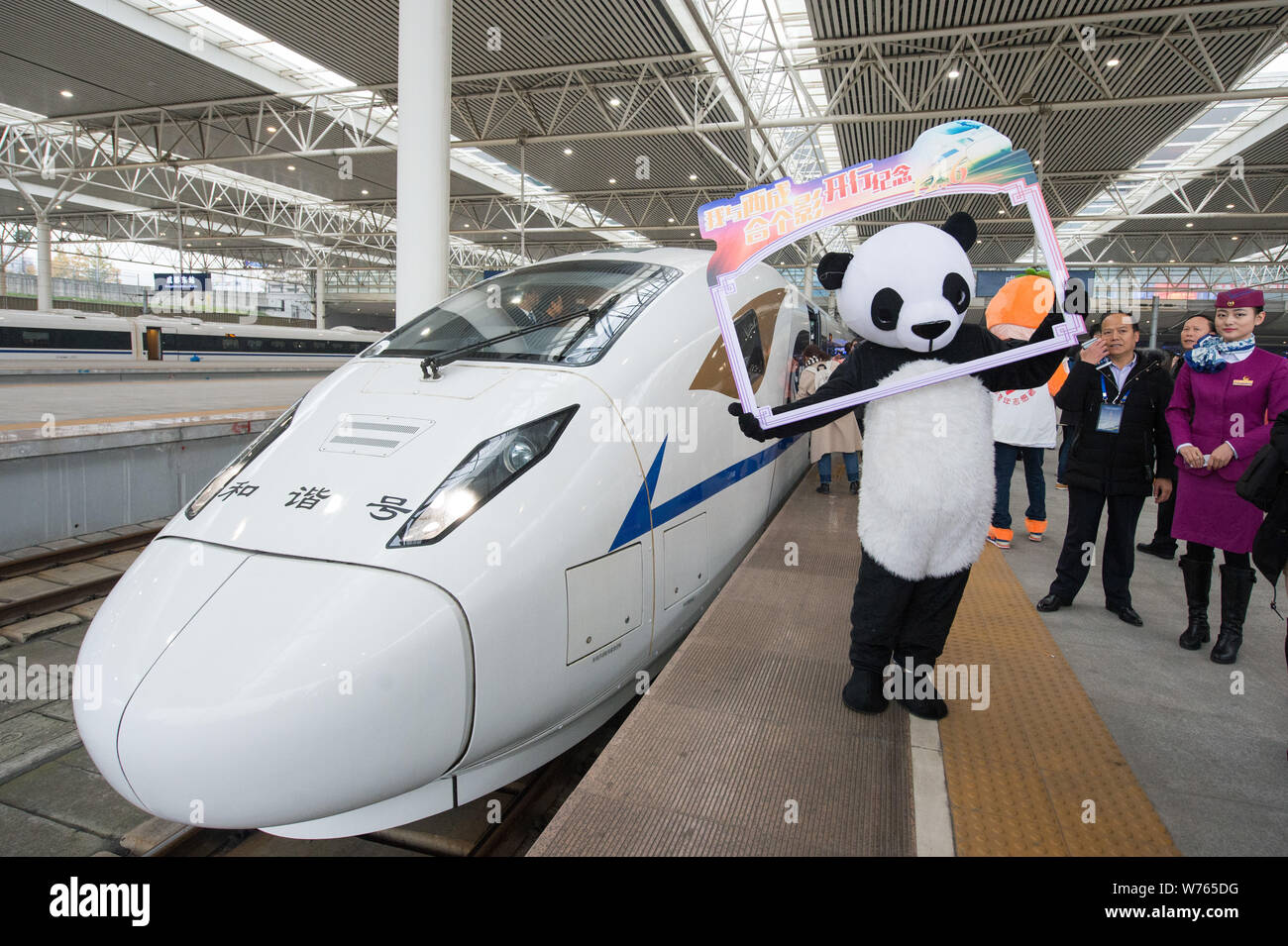 A performer dressed as giant panda welcomes passengers beside a CRH ...