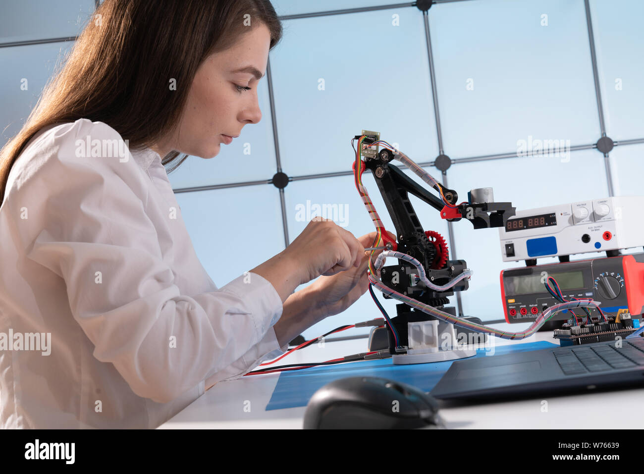 A young woman writes an algorithm for the robot arm. Science Research ...