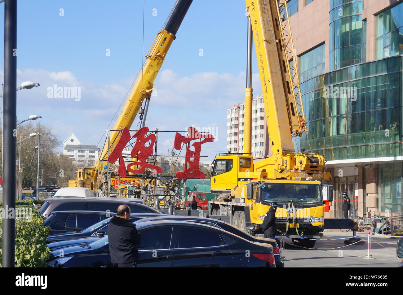 --FILE--Chinese workers operate crane cars to remove a signboard on the ...
