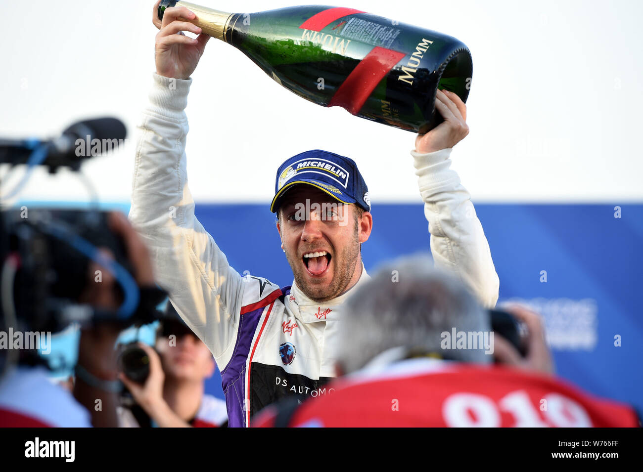 British racing driver Sam Bird of AF Corse holds up a bottle of ...
