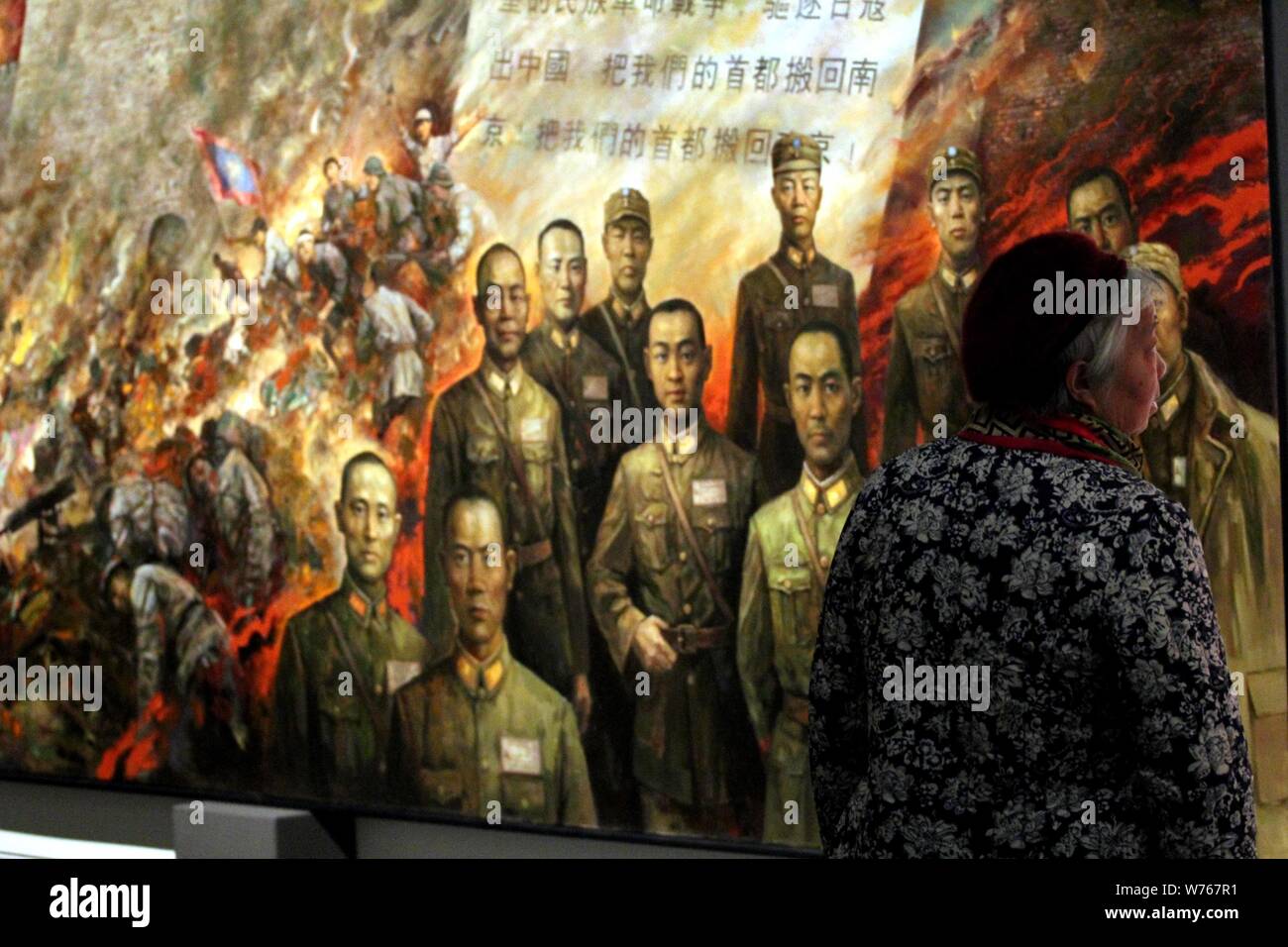 A visitor looks at an oil painting in commemoration of the Nanjing ...