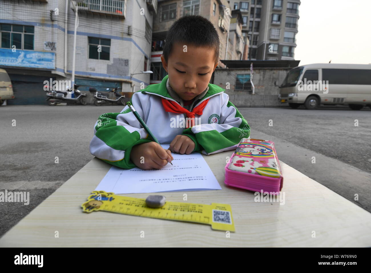 Eight-year-old Chinese boy does homework accompanied by his mother on ...