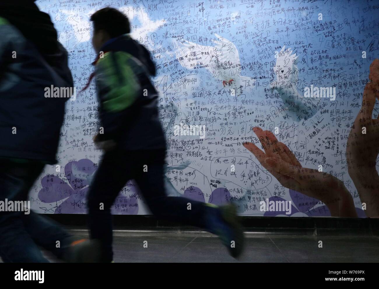 Passengers walk past the the signature wall filled with names signed by ...