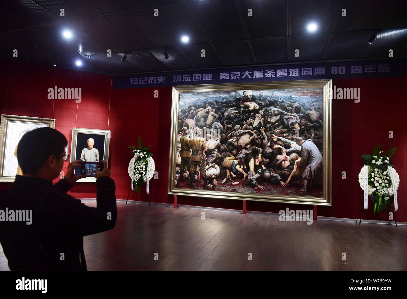 A visitor takes photos of the oil painting "Nanjing Massacre" by US ...