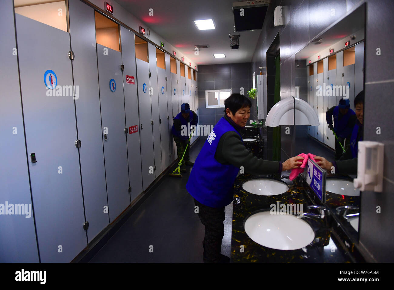 Chinese workers clean up the unisex public toilet in Shenyang city ...