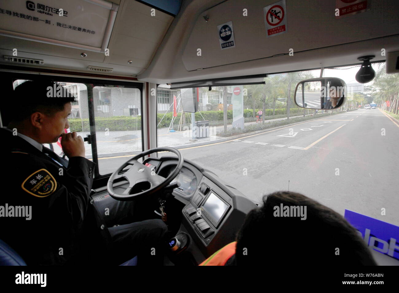 A driver sits in the driver's seat on a self-driving bus during its ...