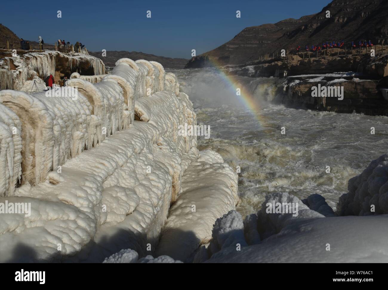 Tourists visit the Hukou Waterfall scenic spot with a rainbow and ...