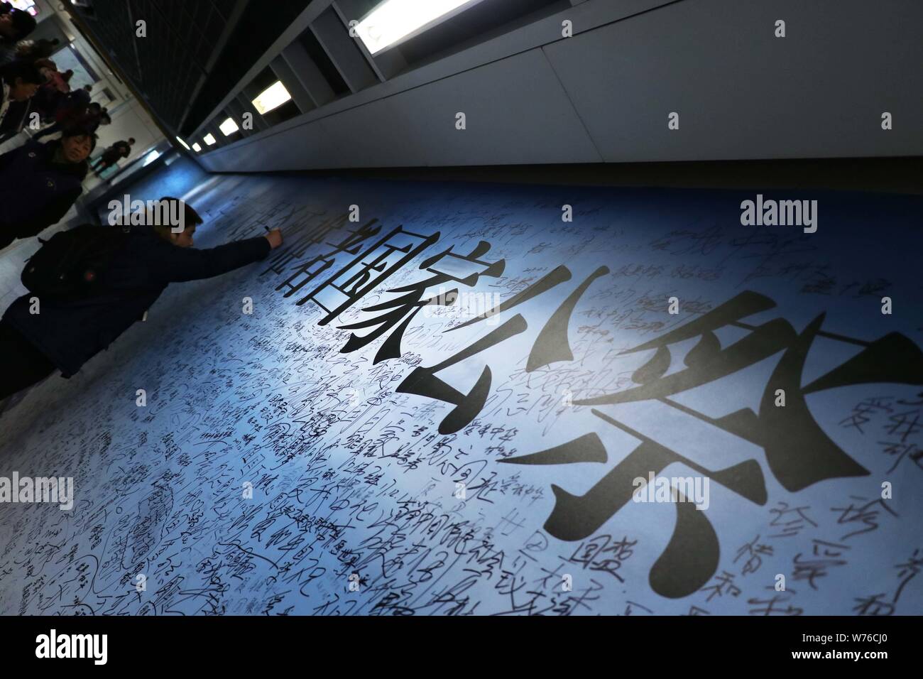 A passenger signs his autograph on the signature wall to pray for peace ...
