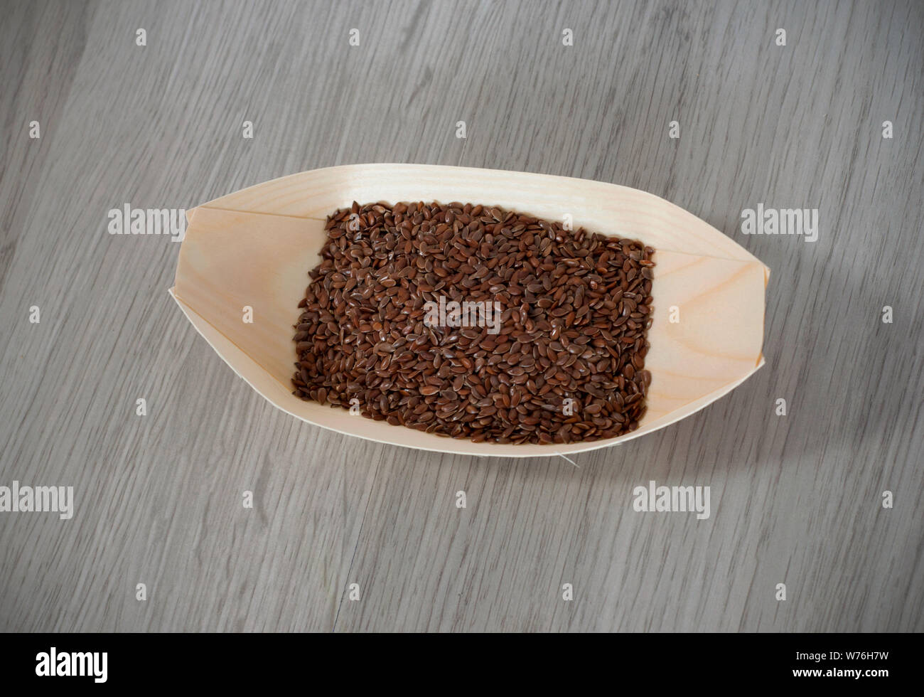 Flax seeds in a eco, wooden container isolated on wooden background ...