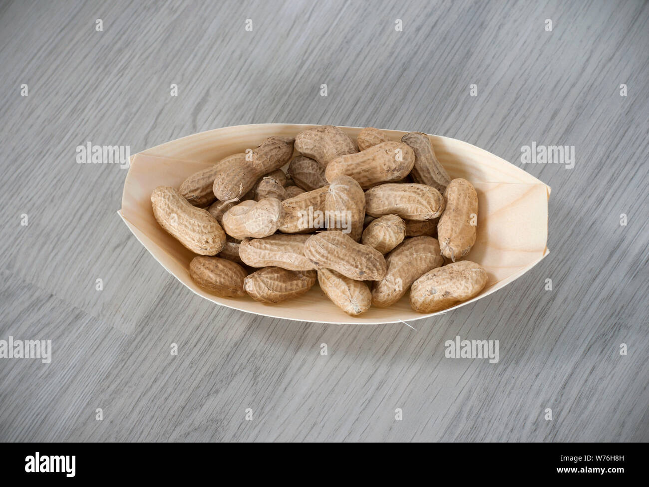 Peanuts in a eco, wooden container isolated on wooden background. Pile ...