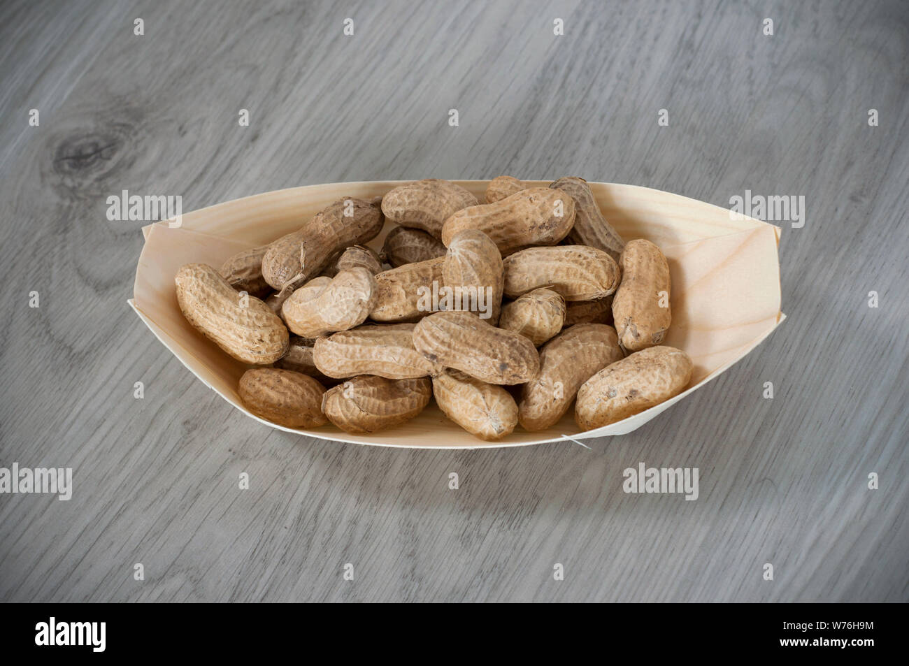 Peanuts in a eco, wooden container isolated on wooden background. Pile ...