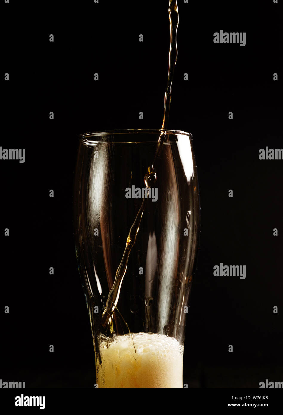 beer pours into glass on black background Stock Photo - Alamy