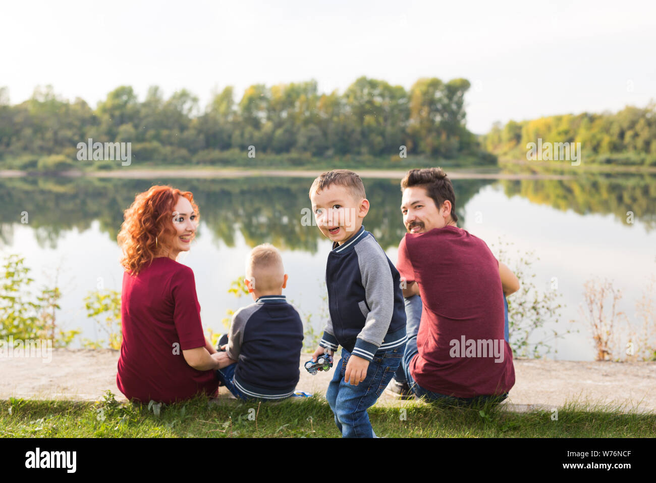 Parenthood, nature, people concept - family with two sons sitting near ...