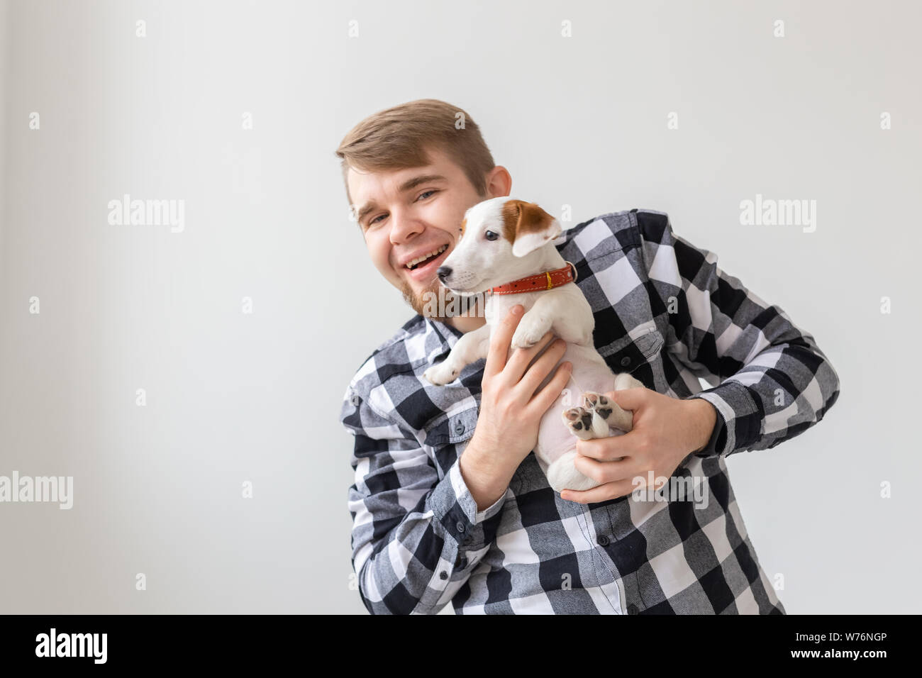 people, pets and dogs concept - young man hugging funny puppy on white ...