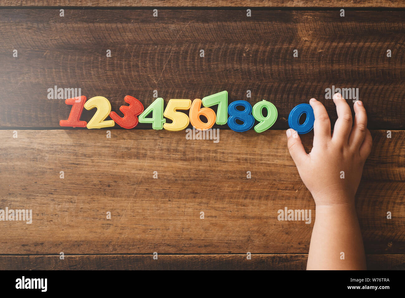 Child hand holding number zero with sets of other colorful numbers ...