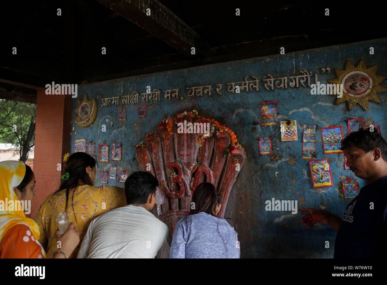 Devotees worship an idol snake god at the Nagpokhari during a Festival ...
