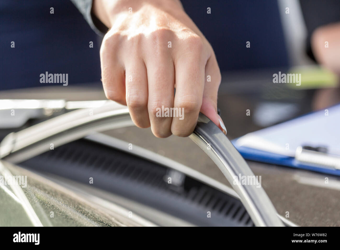 Girls hand regulates and inspects the wipers on the glass of the car ...