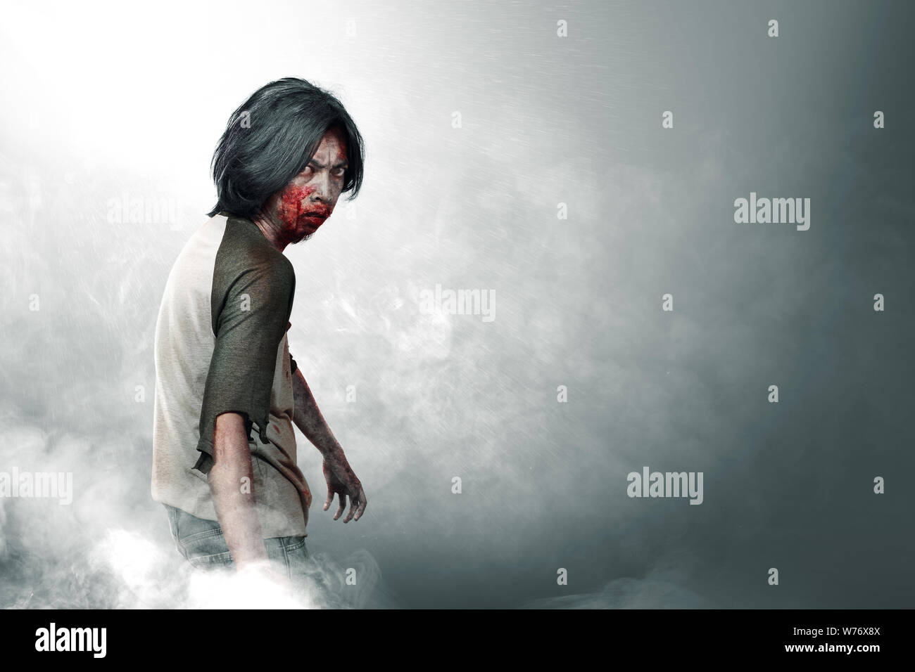 Scary zombies with blood and wound on his body walking amid the fog ...