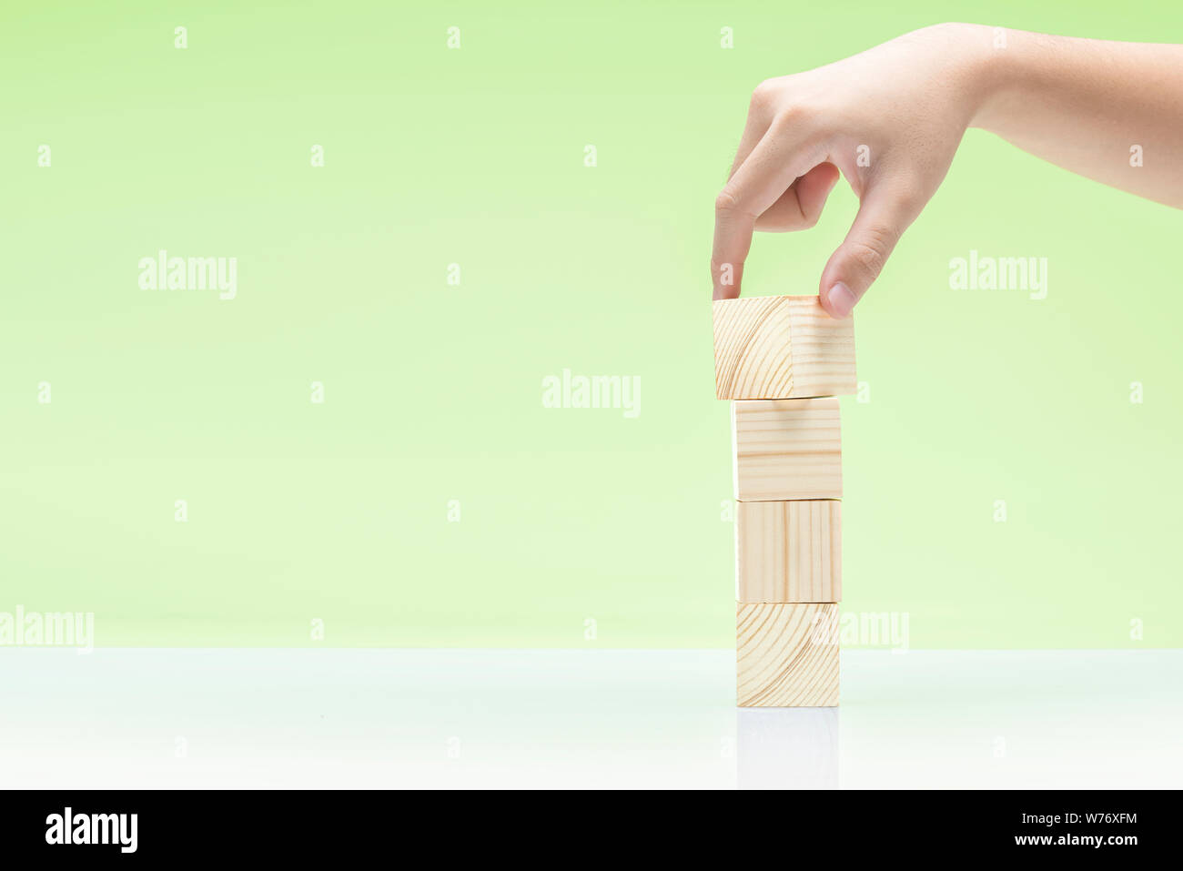 Hand build a stack of wooden block toy on the table over green ...
