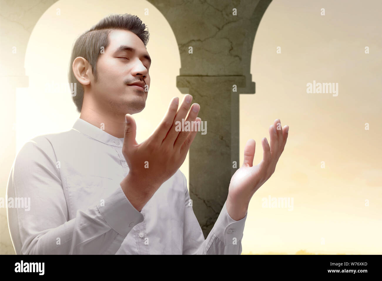 Asian Muslim man standing and praying while raised arms inside the ...