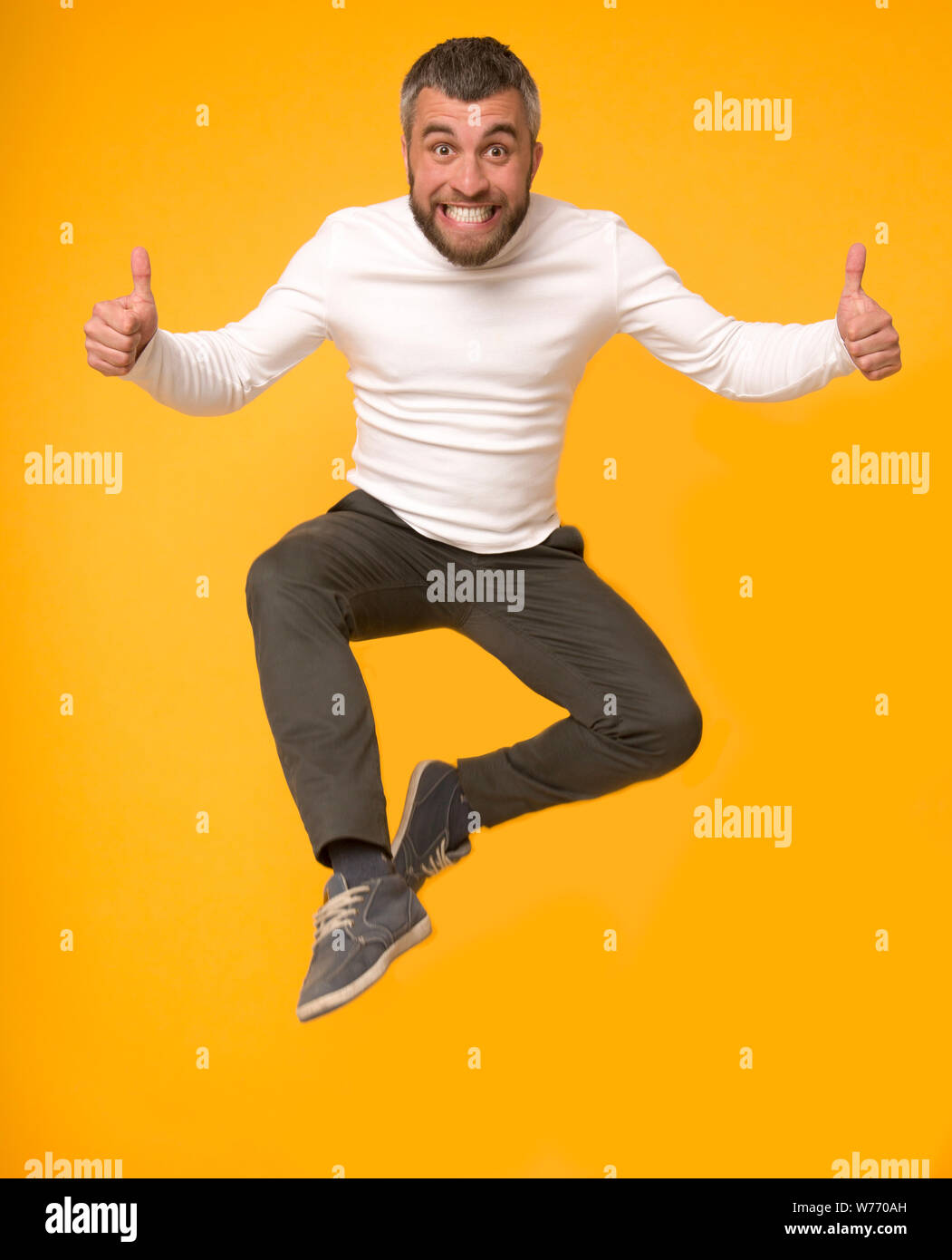 Joyful caucasian man jumping in the air with thumbs up Stock Photo - Alamy