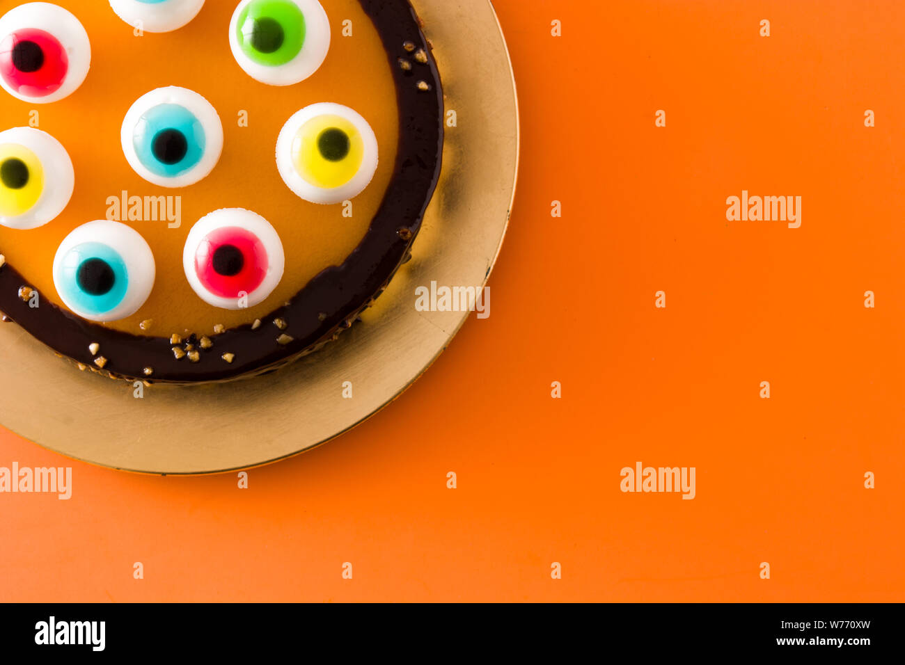 Halloween cake with candy eyes decoration on orange background.Top view ...