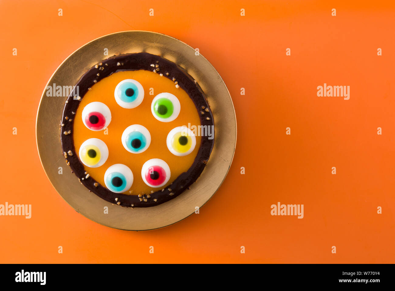 Halloween cake with candy eyes decoration on orange background.Top view ...