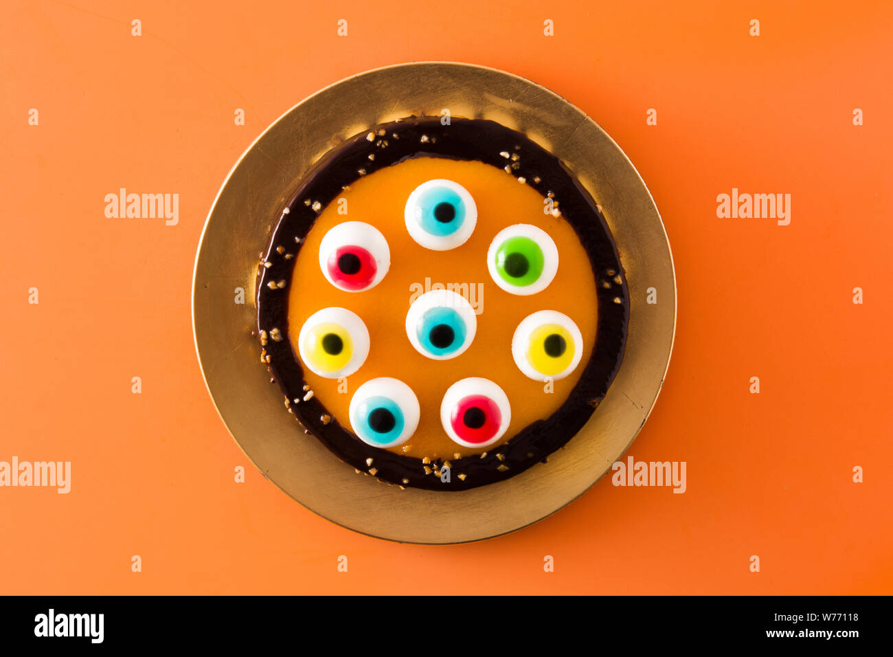 Halloween cake with candy eyes decoration on orange background.Top view ...