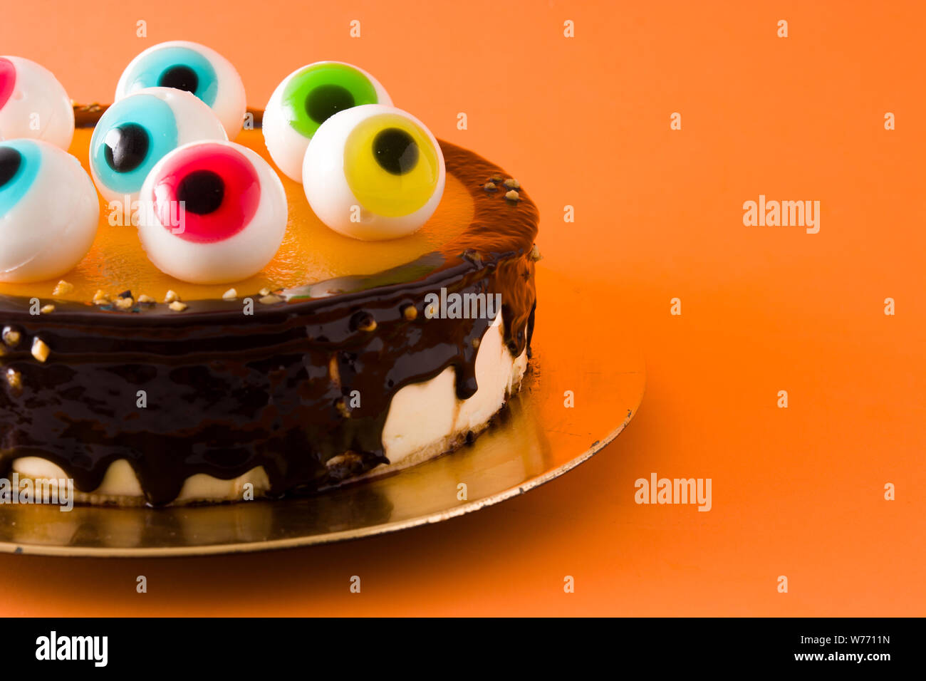 Halloween cake with candy eyes decoration on orange background ...