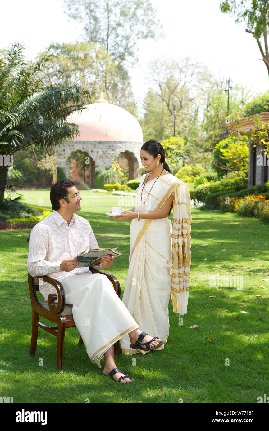 Young woman giving a cup of tea to her husband Stock Photo - Alamy