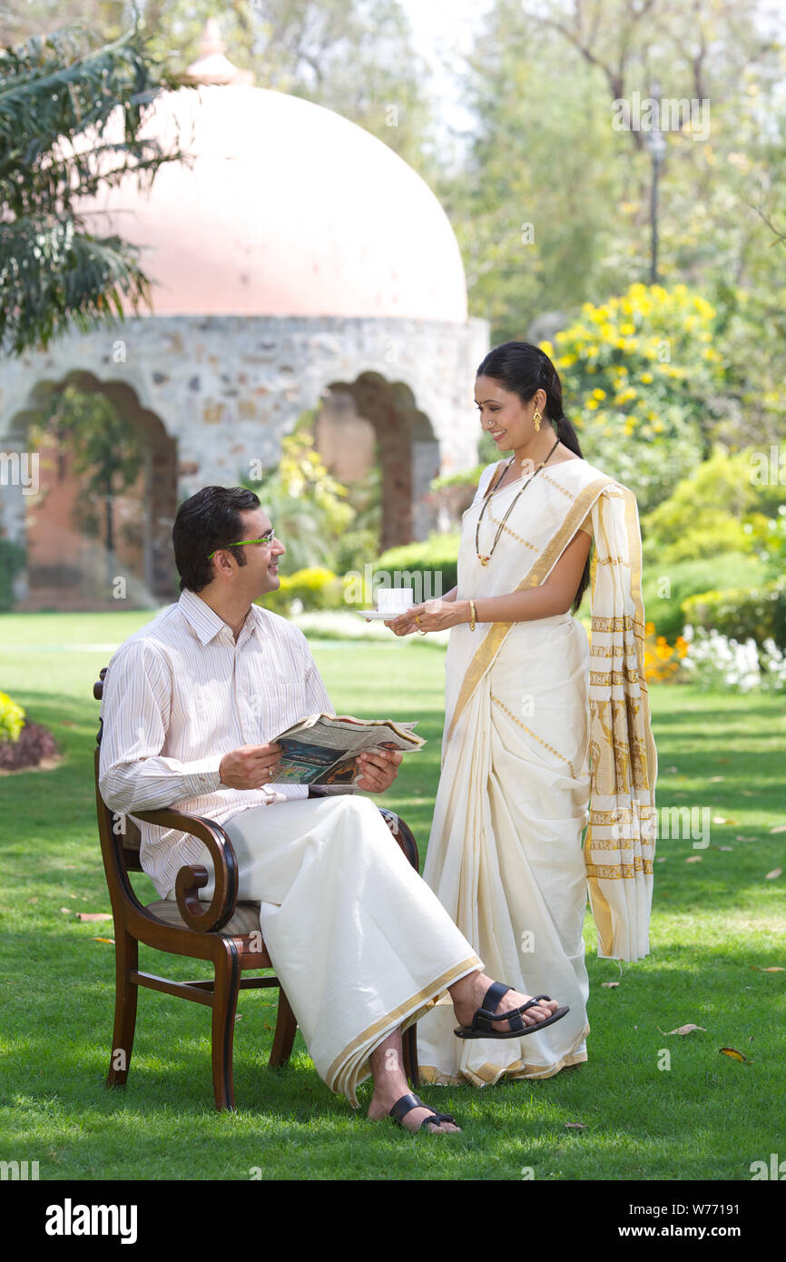 Young woman giving a cup of tea to her husband Stock Photo - Alamy