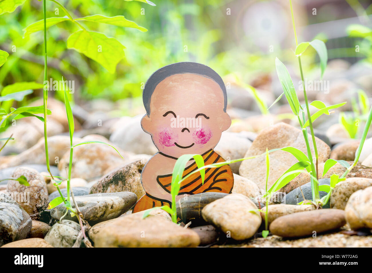 Little boy Buddhist, little Buddha, sitting on the sand on stones and ...