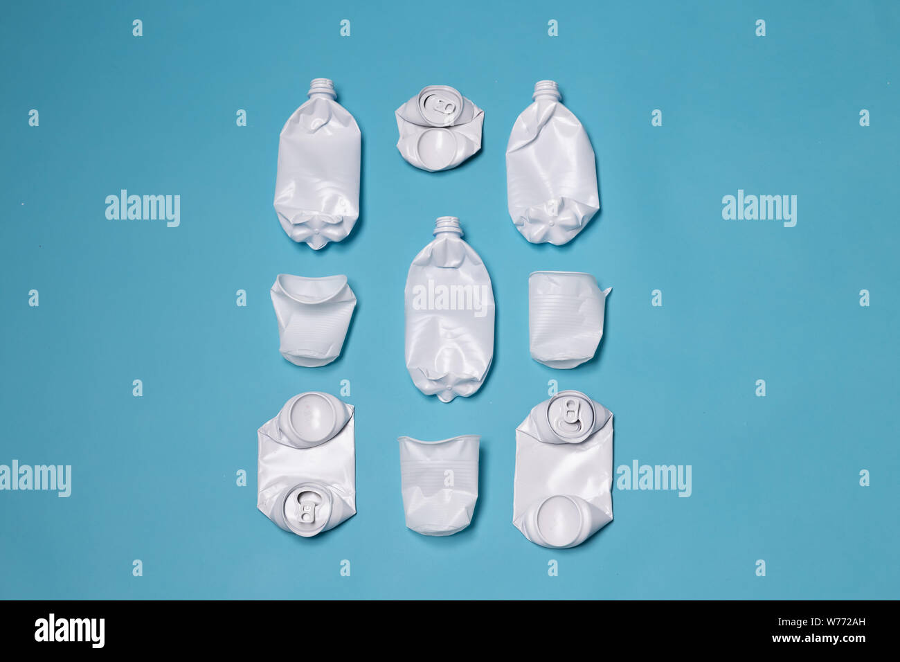 Crumpled plastic and metal cans lie on a blue background. Concept of ...