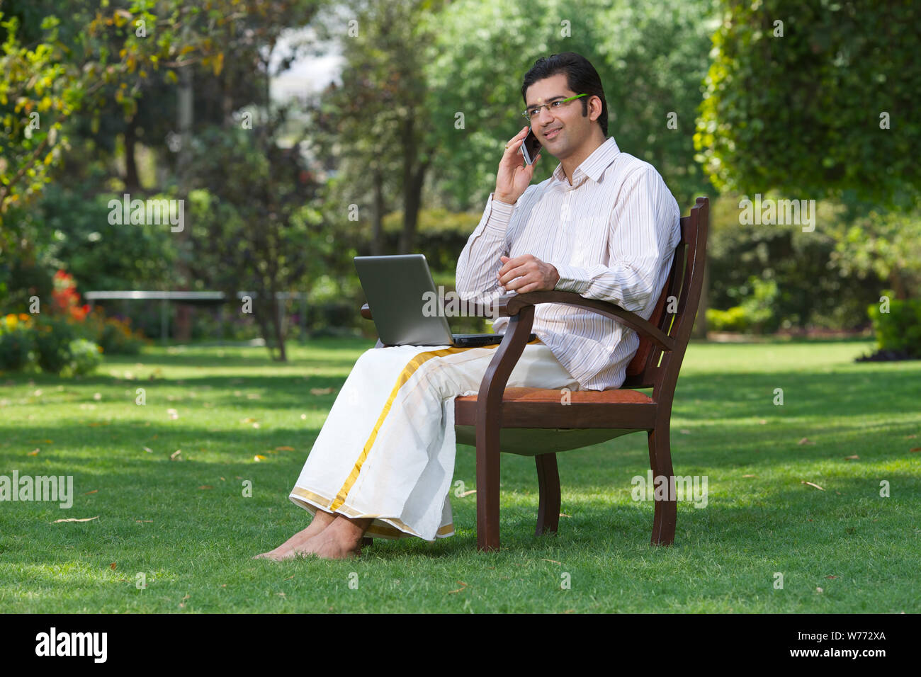 South Indian man talking on mobile phone and using laptop Stock Photo ...
