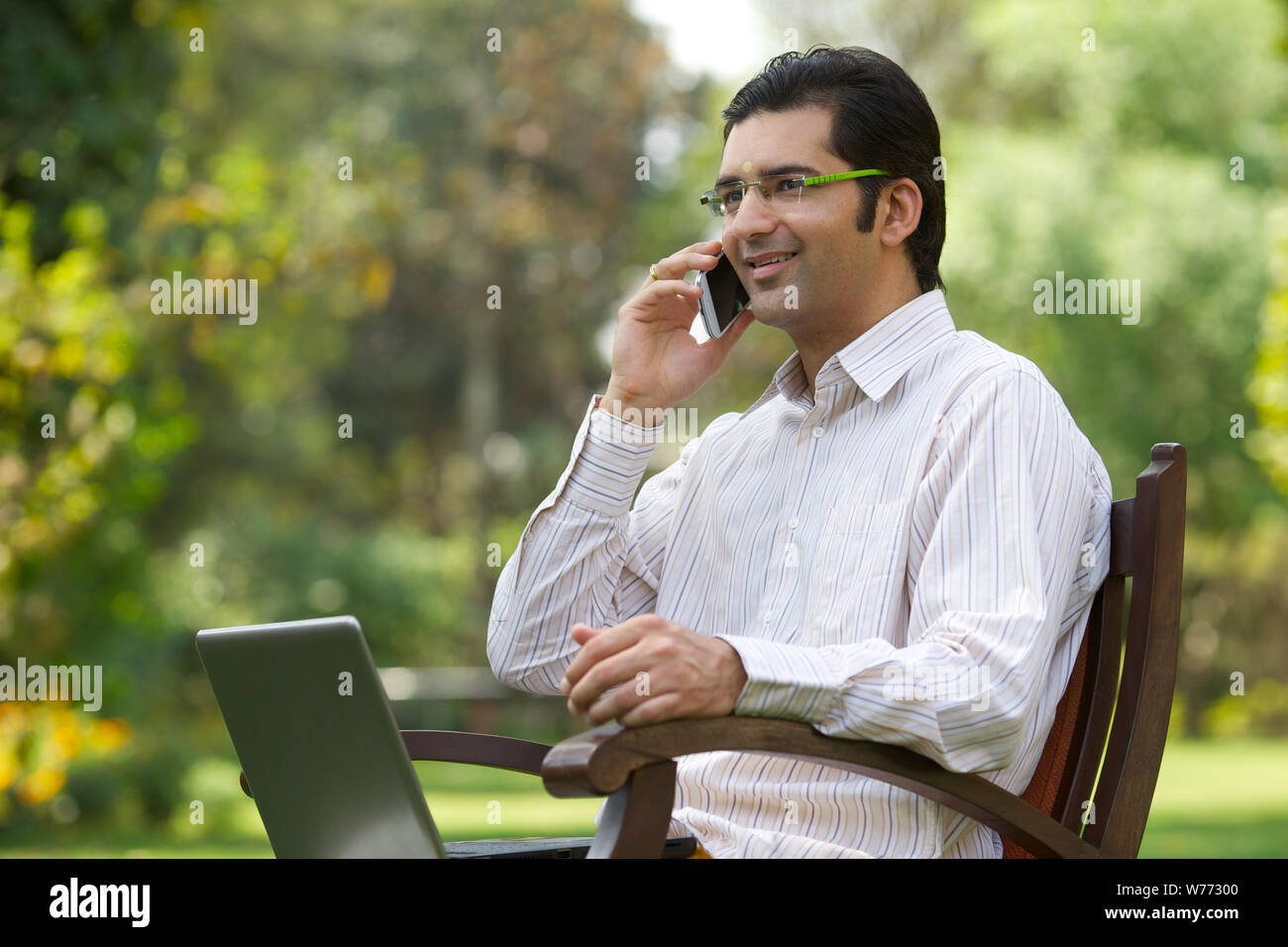 South Indian man talking on mobile phone and using laptop Stock Photo ...