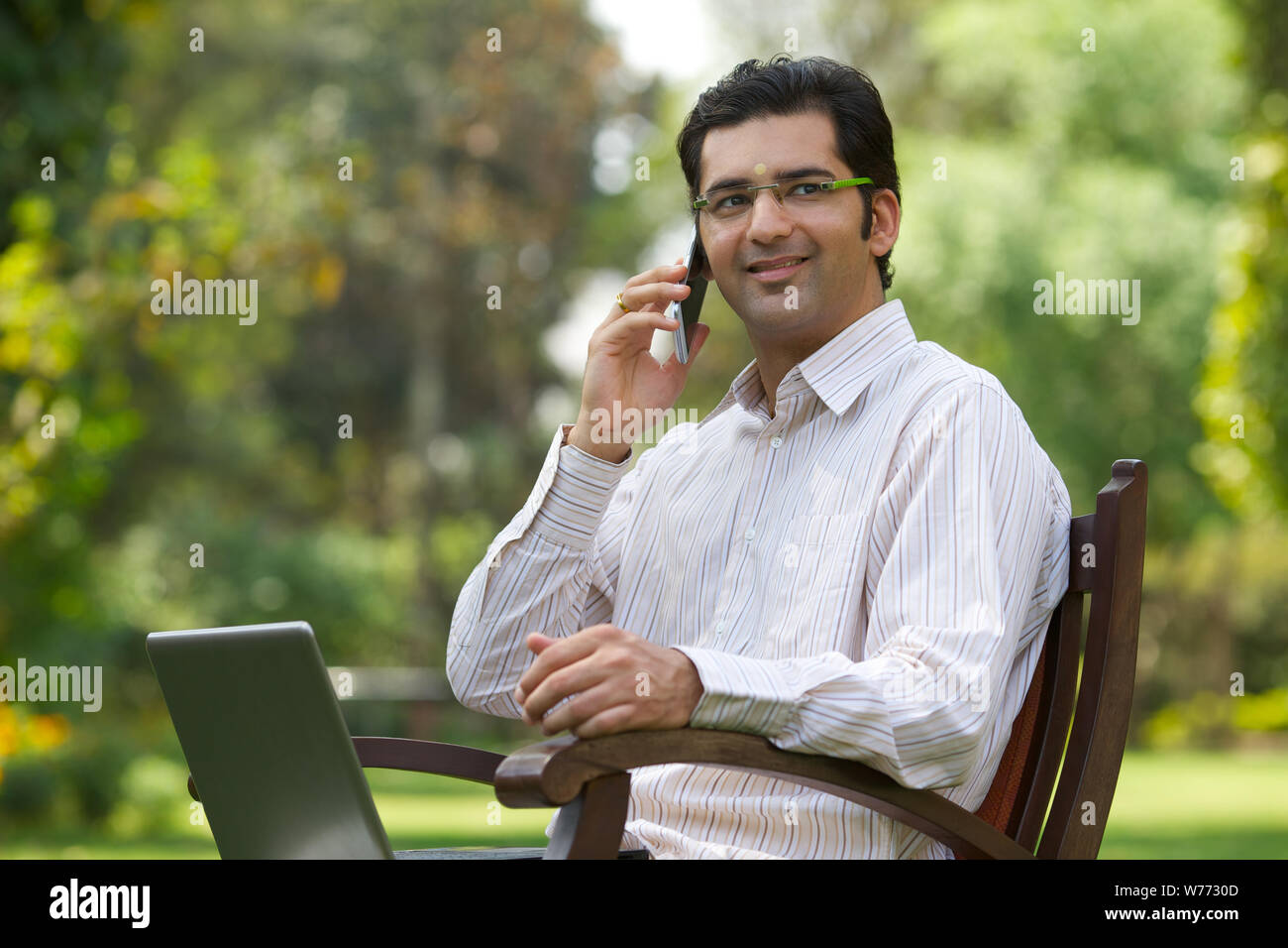South Indian man talking on mobile phone and using laptop Stock Photo ...