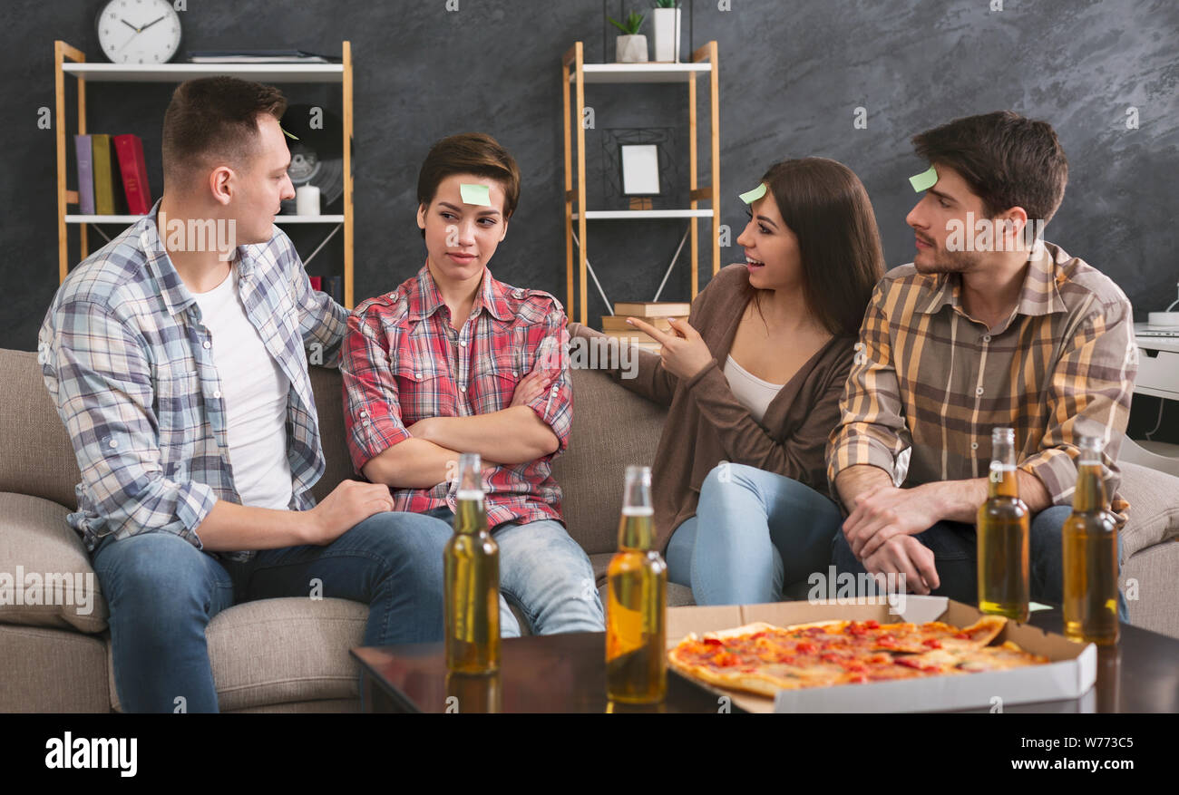 Four friends playing game guess who i am at home Stock Photo - Alamy