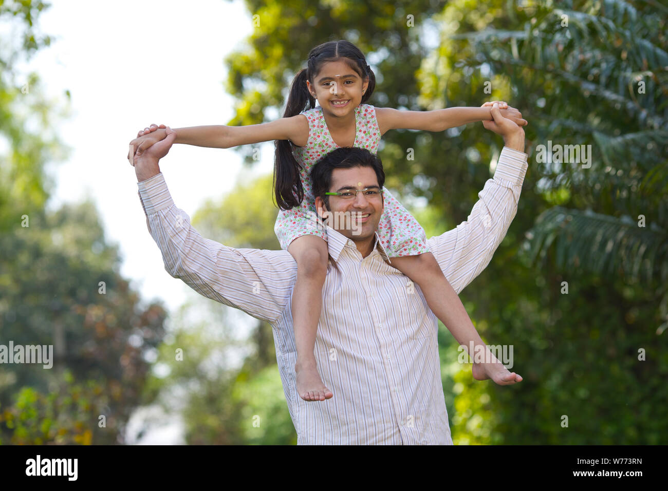 South Indian man carrying his daughter on his shoulders Stock Photo - Alamy
