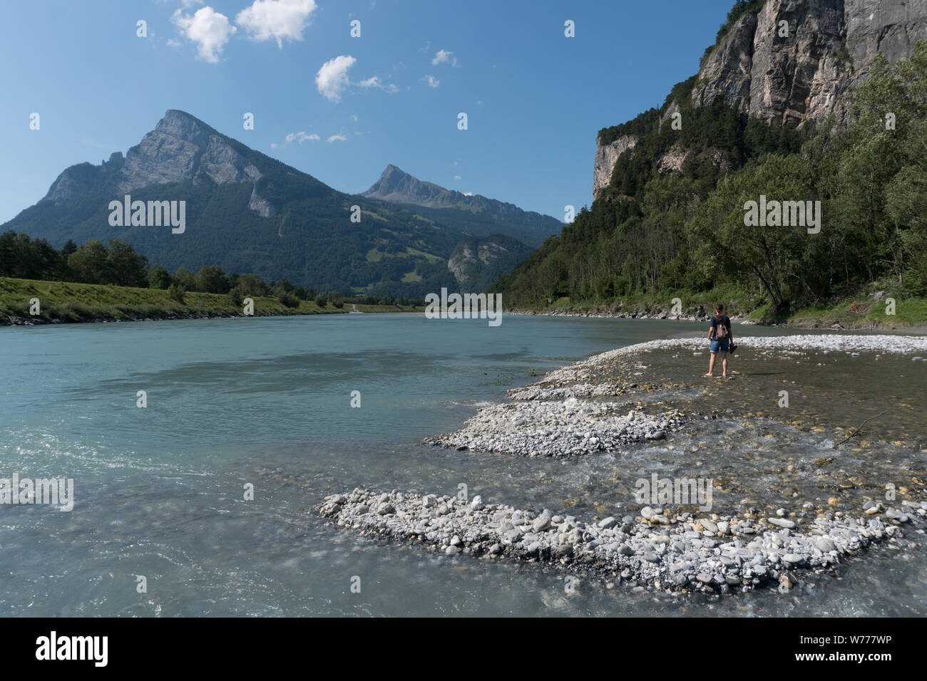 young woman standing in the middle of the Rhine river and Swiss Alps ...