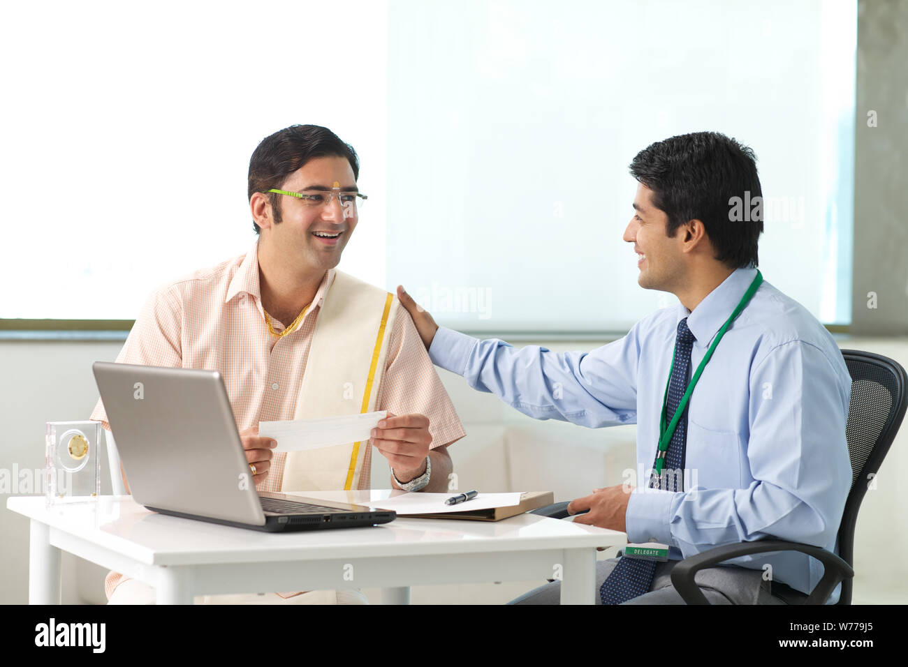 South Indian man sitting with a bank manager and holding his cheque of ...