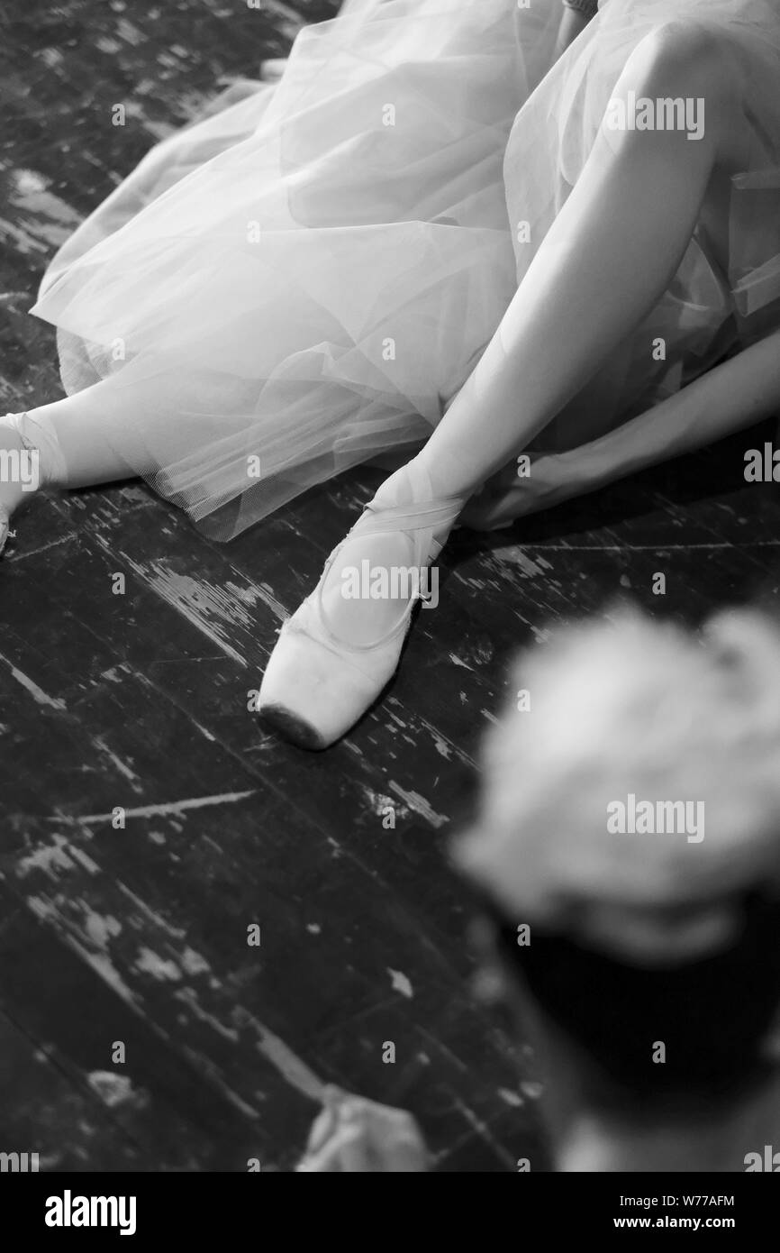 Ballerina is resting sitting on the floor in the rehearsal hall of the ...