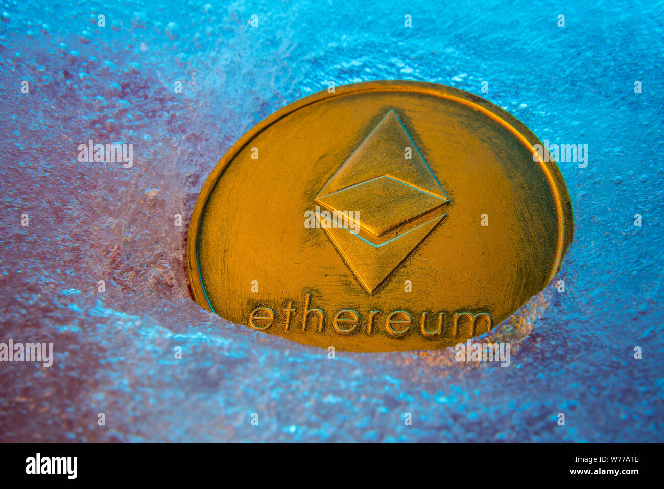 Golden Ethereum coin, online digital currency frozen in the blue ice ...