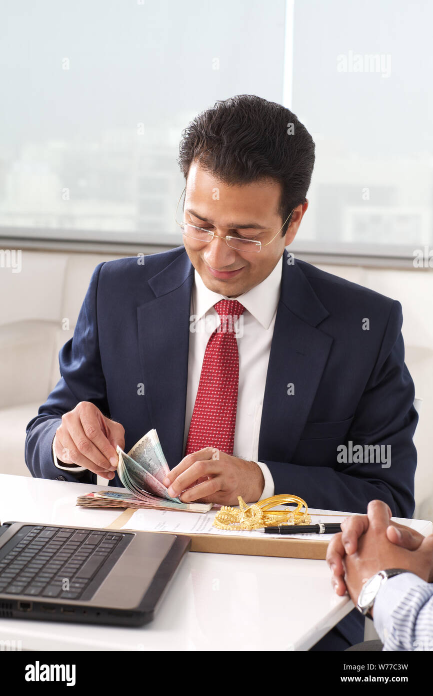 Businessman counting money of gold loan Stock Photo - Alamy