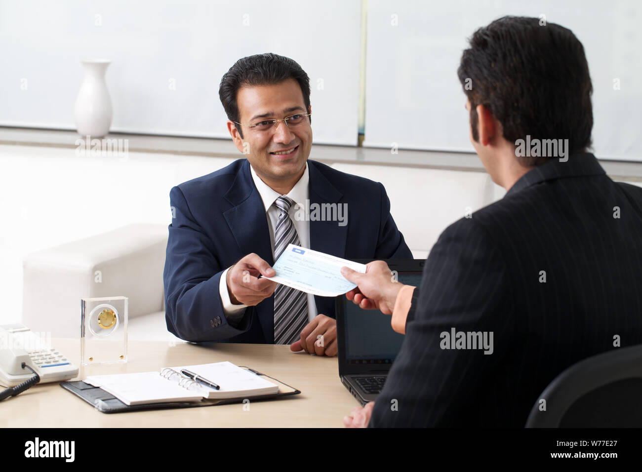 Bank manager giving cheque to his customer as loan Stock Photo - Alamy