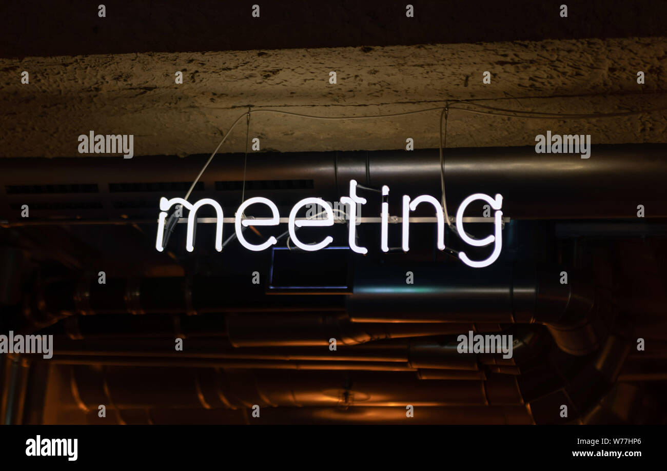 Luminous neon light that forms the word "meeting Stock Photo - Alamy