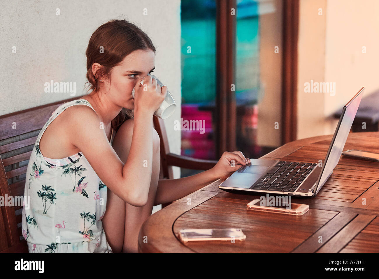 Woman working at home, using portable computer, sitting on patio on ...