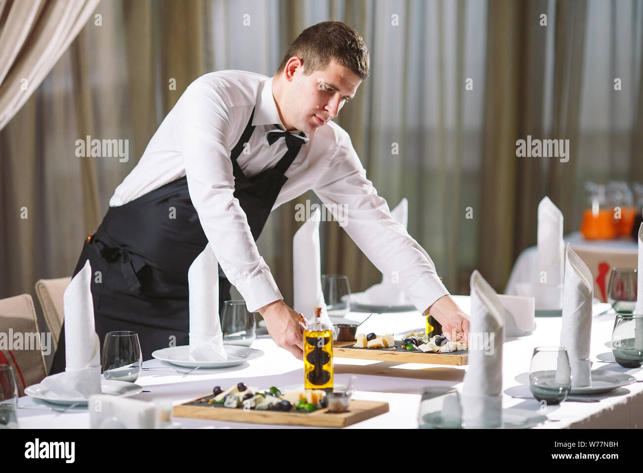 Waiter serving table in the restaurant preparing to receive guests ...