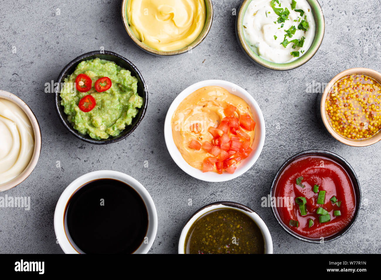 Set of different sauces in bowls on gray rustic concrete background ...