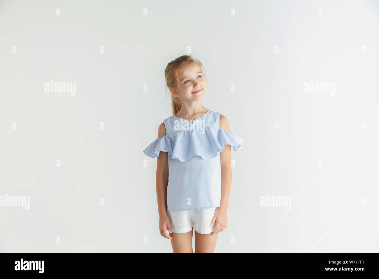 Stylish little smiling girl posing in casual clothes isolated on white ...